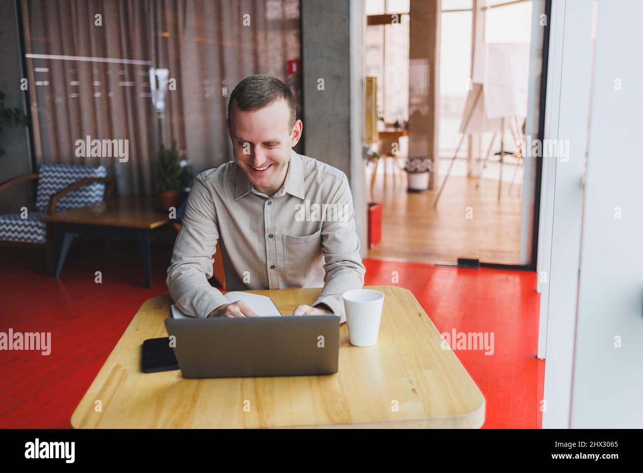 A young man sits at a table and opens a laptop computer while studying ...