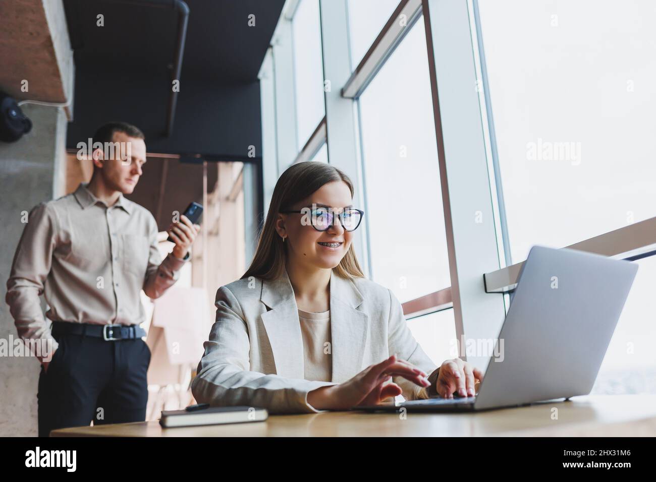 Cheerful female manager in a jacket doing office work and a smiling ...