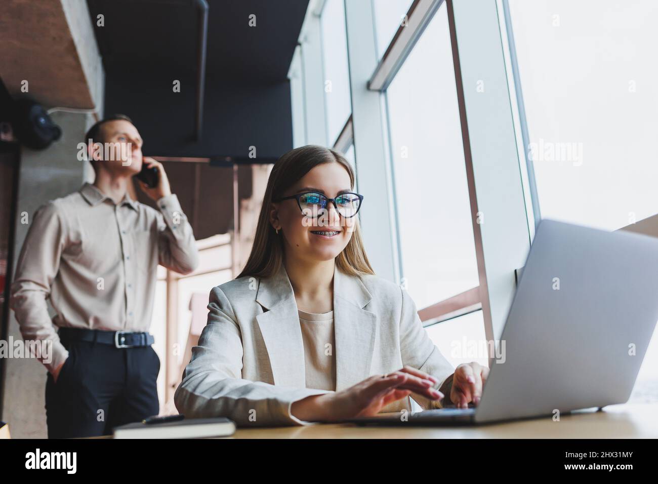 Cheerful female manager in a jacket doing office work and a smiling ...
