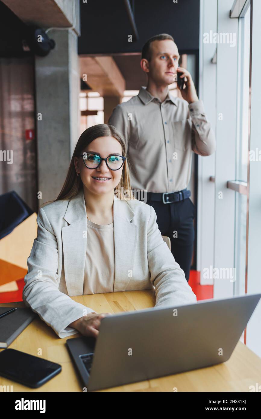 Cheerful female manager in a jacket doing office work and a smiling ...