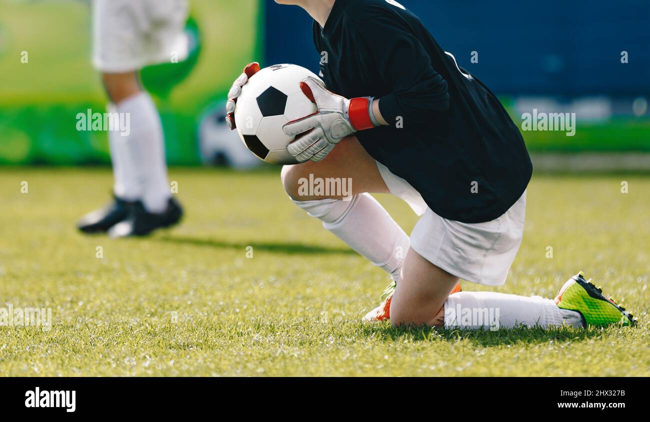 School boy as a soccer goalie catching football ball during a ...