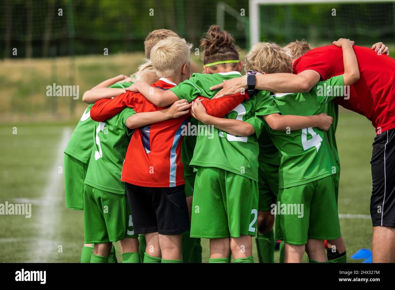 Happy sports team with a young coach. Children playing a football game ...