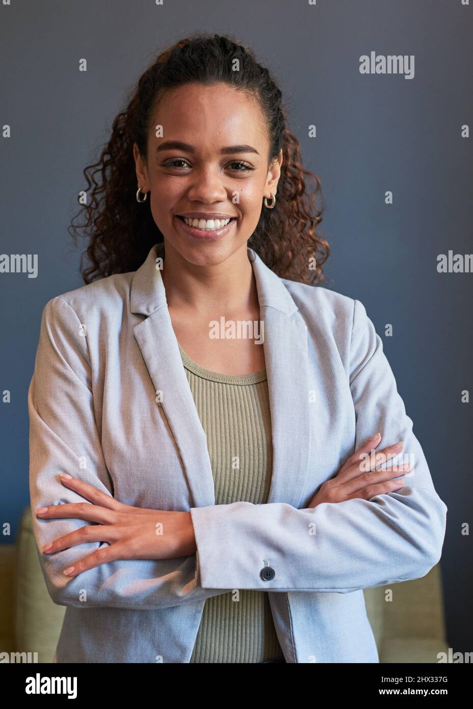 A young business woman stands with her arms crossed in a portrait pose ...