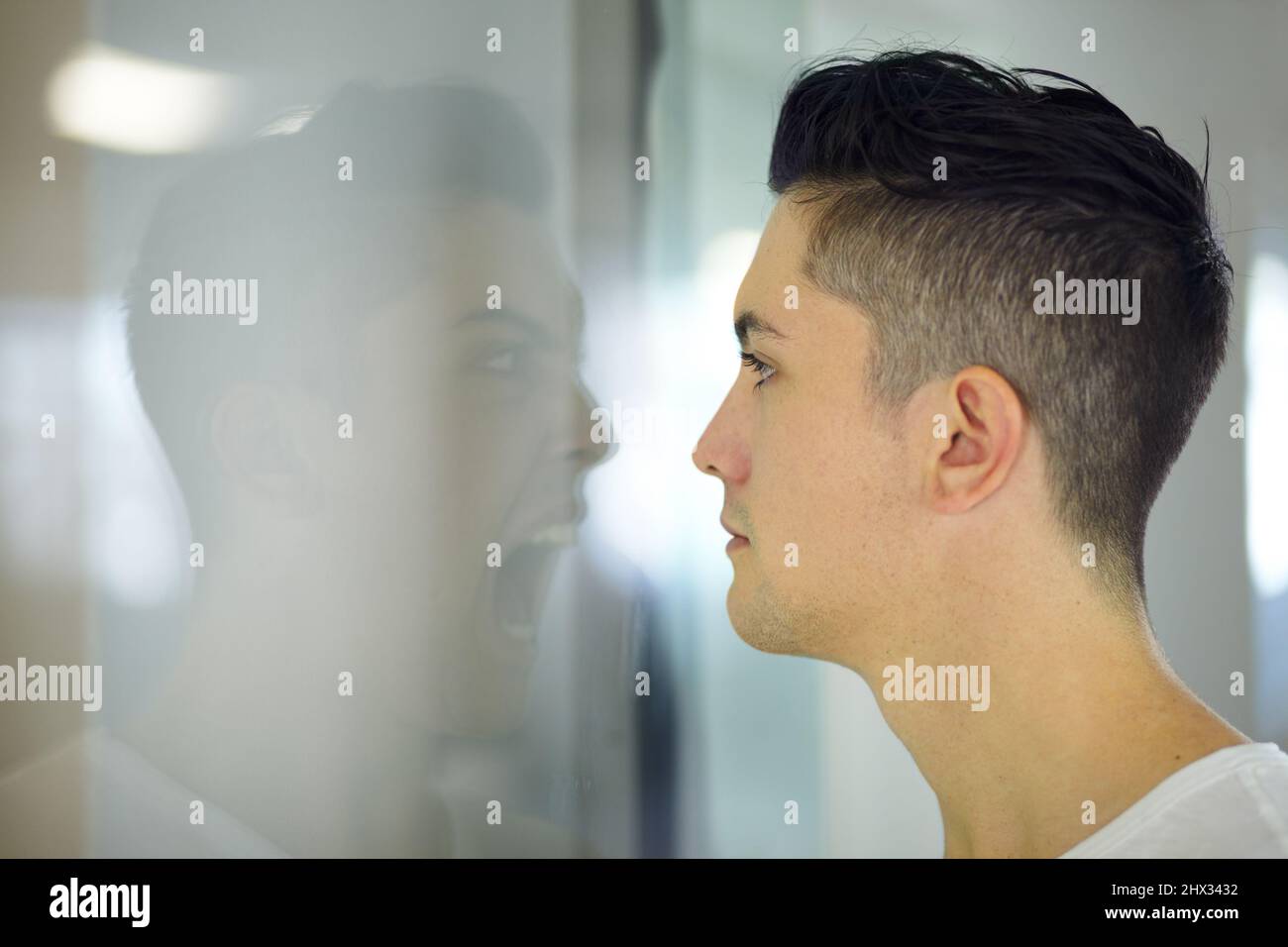 Screaming inside. Young man looking at a screaming reflection of ...