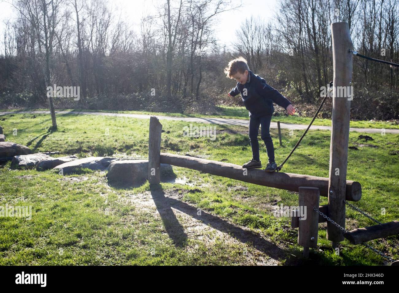 A young boy almost loses his balance on a wooden beam on an obstacle ...