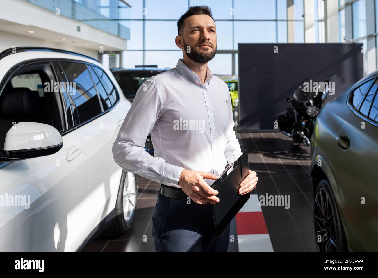 confident businessman filling out paperwork for buying a new car at a ...