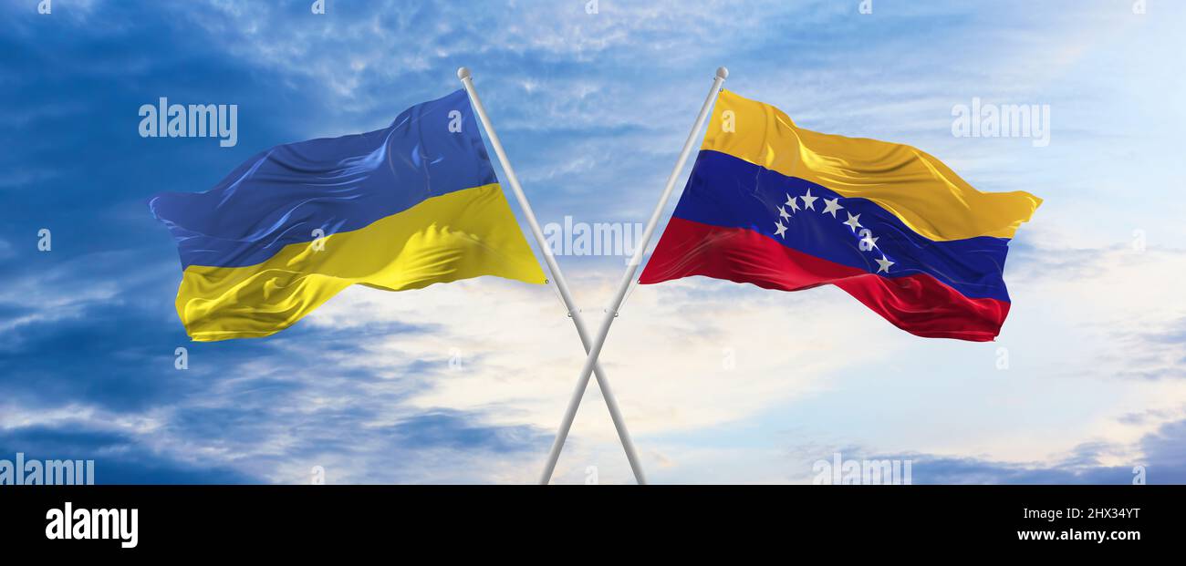 two crossed flags Venezuela and Ukraine waving in wind at cloudy sky ...