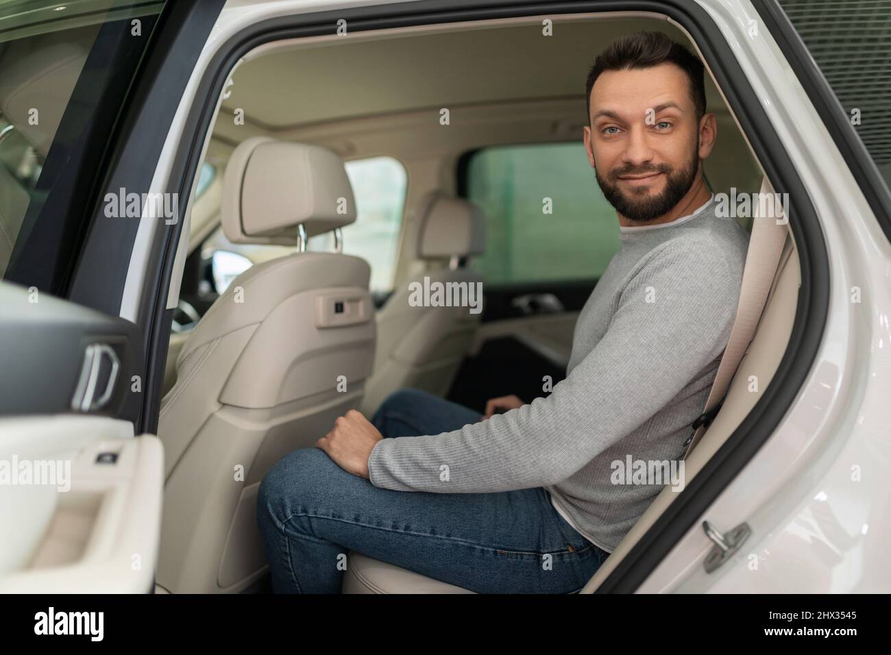 a customer in a car dealership sits in the back seat of a car with a ...