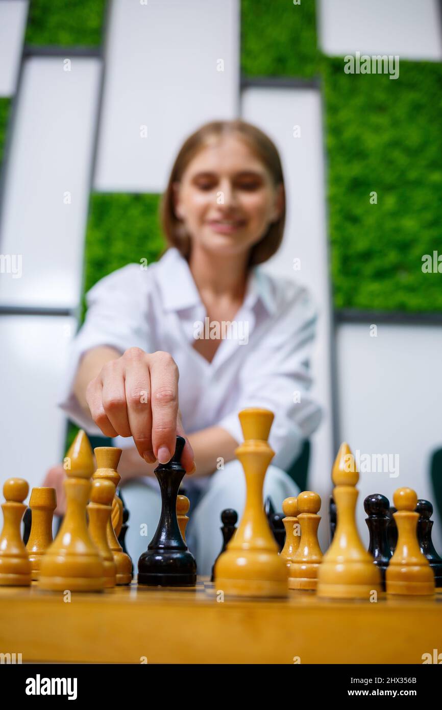 Confident business woman playing chess at the table. Intellectual duel ...
