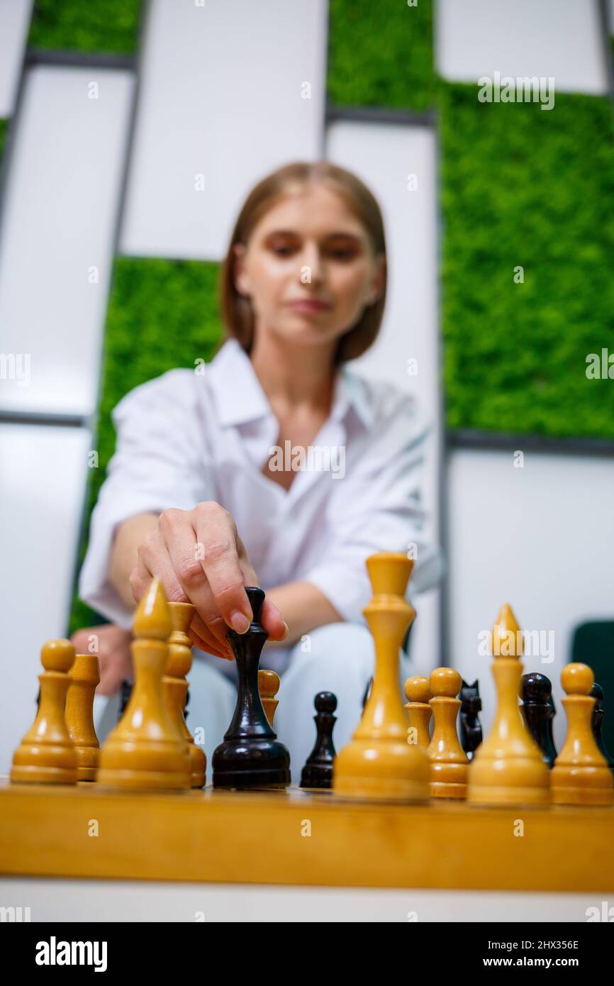 Confident business woman playing chess at the table. Intellectual duel ...
