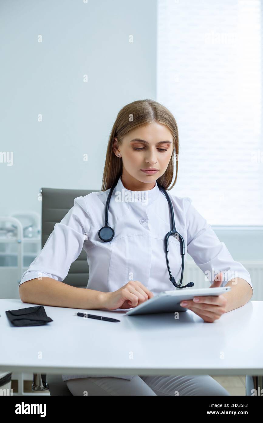 A beautiful modern female doctor in a white medical coat with a ...