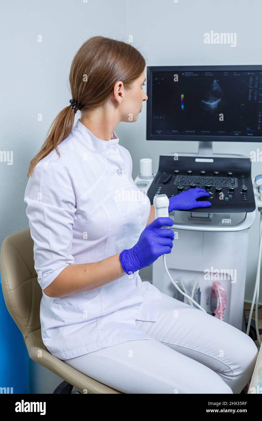 A young woman is an intern doctor, she is in a white suit and medical ...