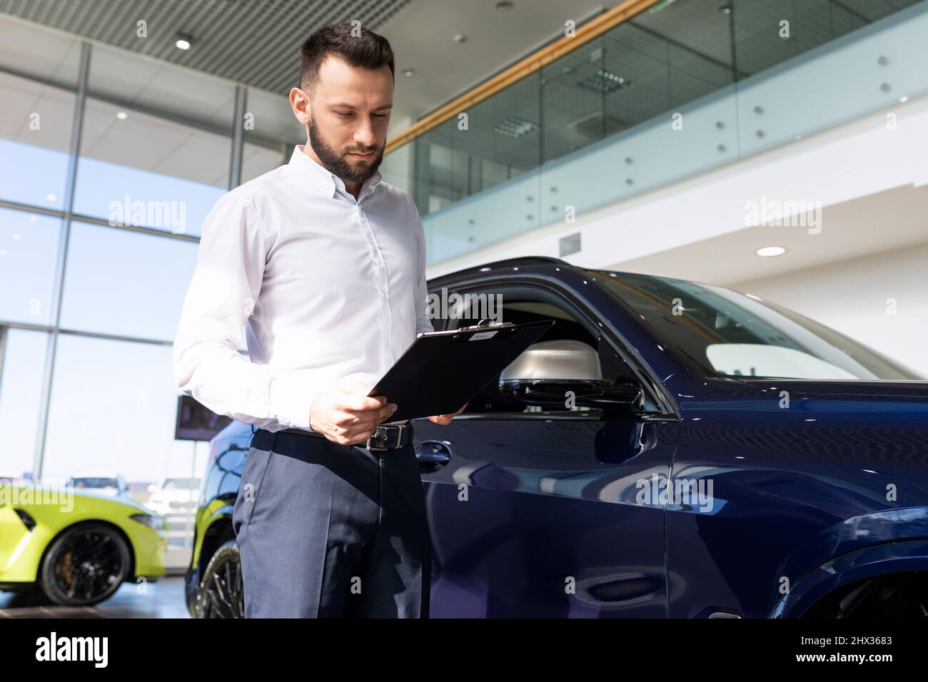 the seller at the car dealership prepares documents for the buyer of ...