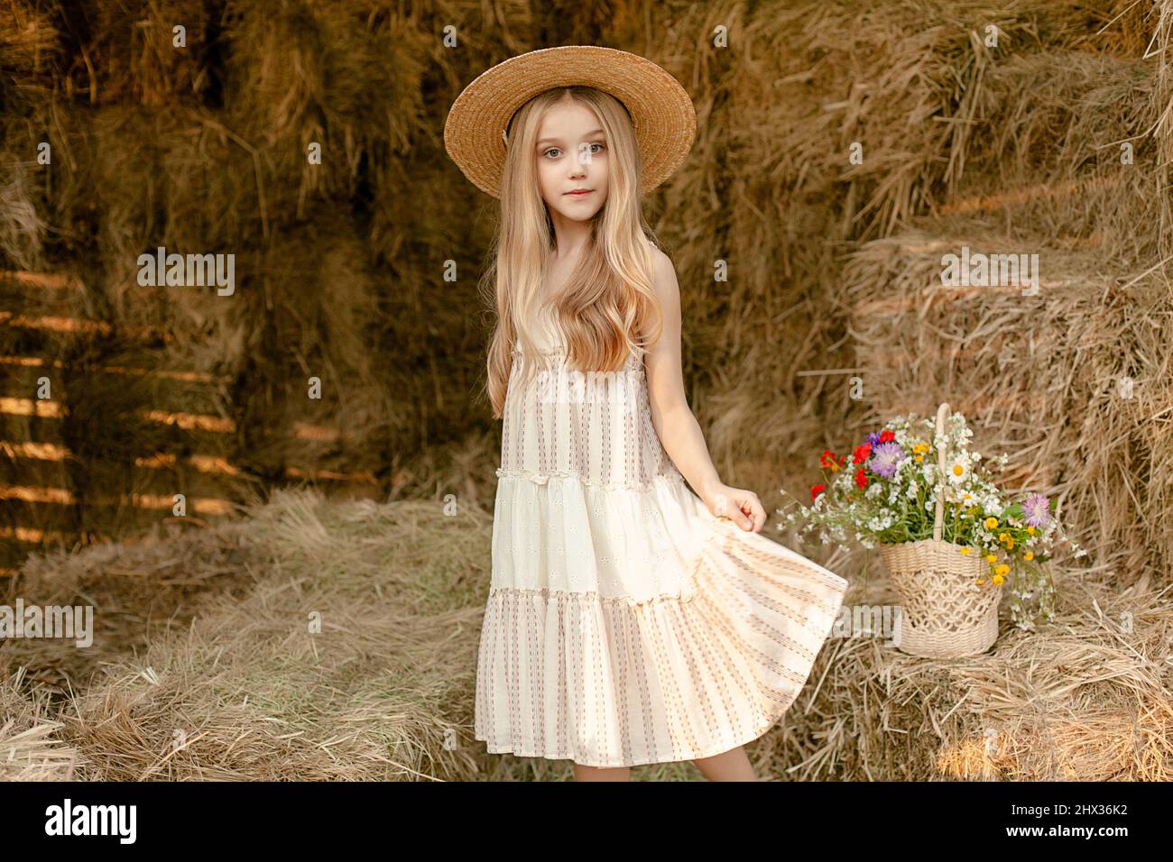 Tween girl enjoying summer vacation in countryside, posing on hayloft ...