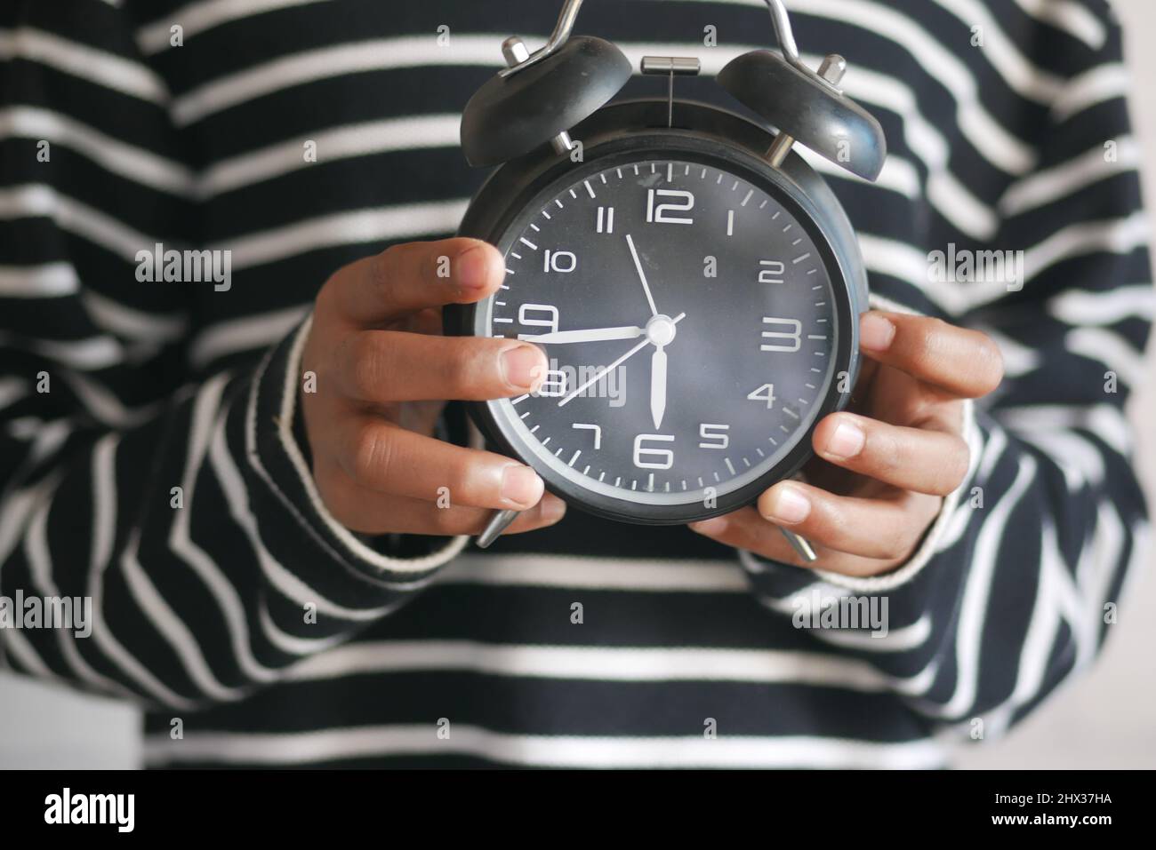 person hand holding alarm clock white background Stock Photo - Alamy
