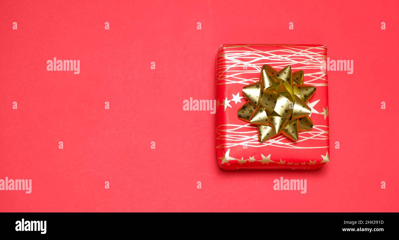 Red square gift box with gold bow, banner with text space, top view ...