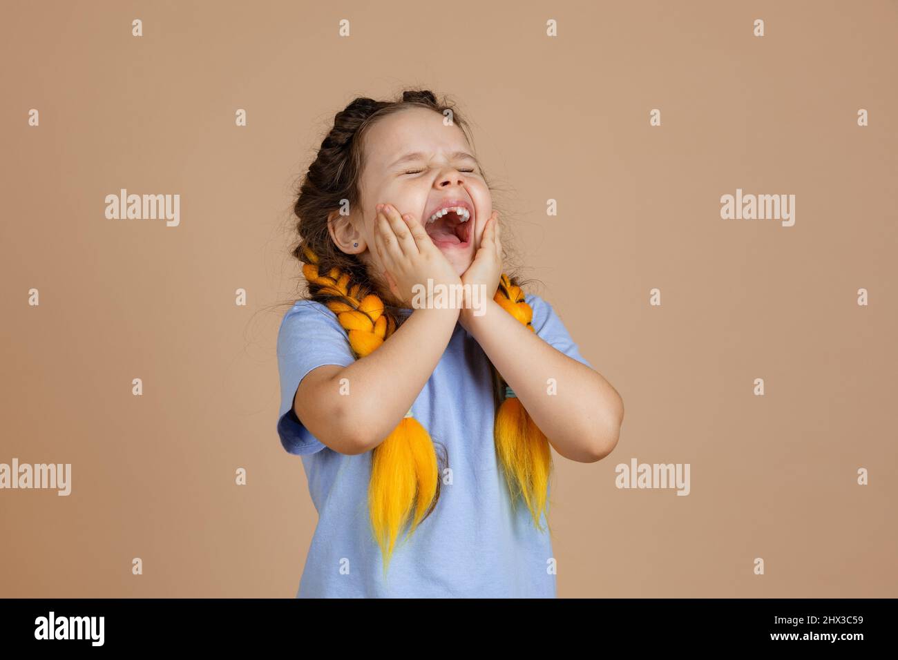 Shouting sad young girl with opened mouth touching face with hands ...