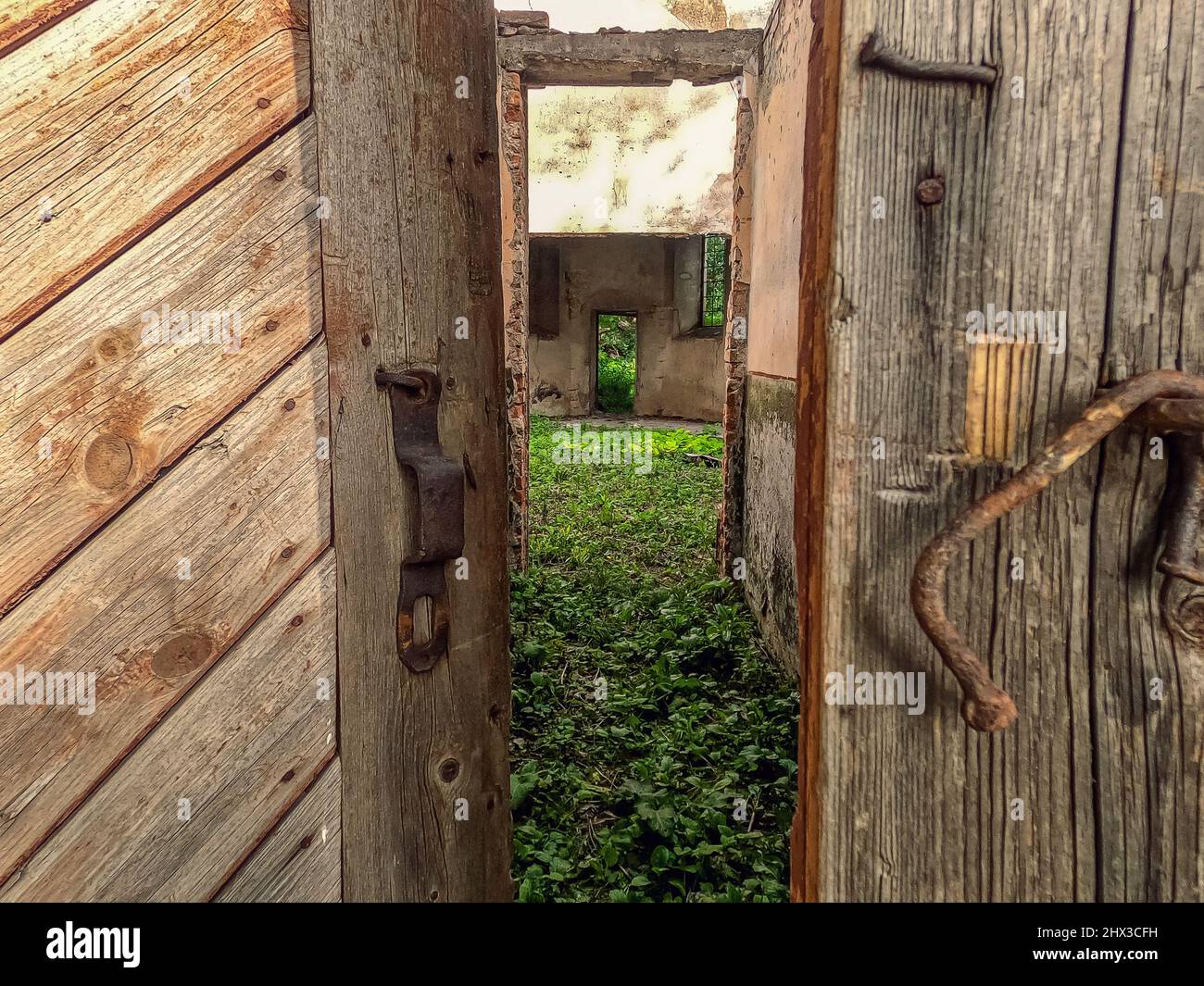 View of empty abandoned courtyard through wooden doors of old ruined ...