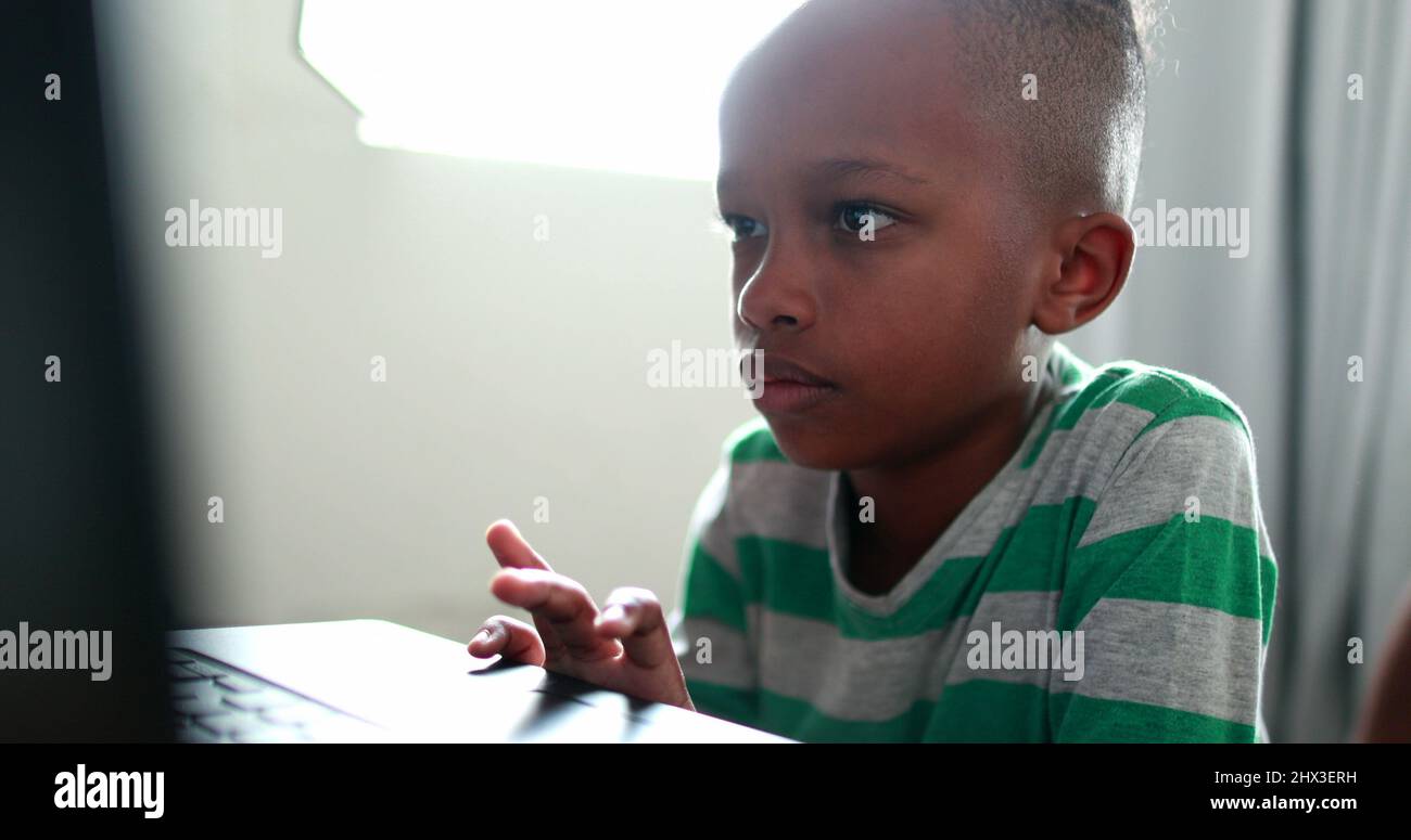 African boy studying from home in front of laptop computer Stock Photo ...