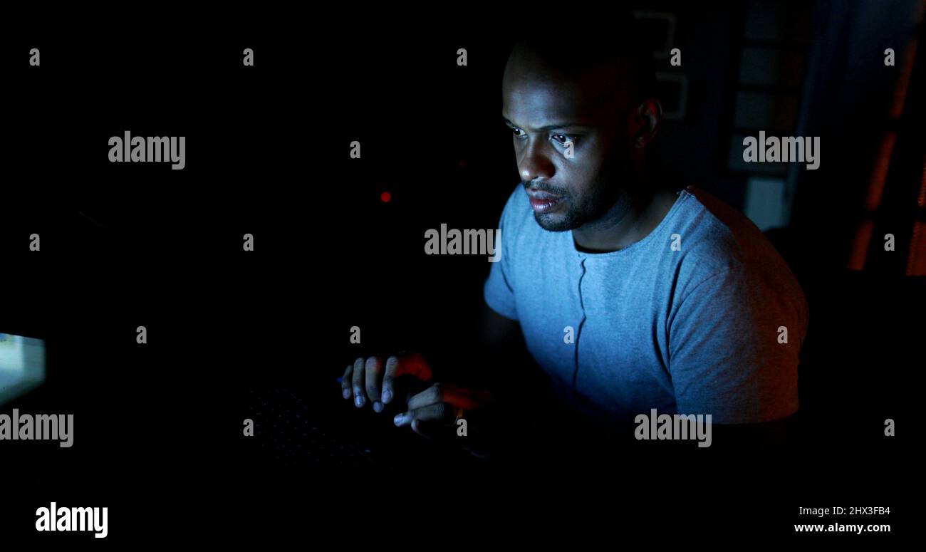 African man looking at laptop screen at night in the dark, person ...