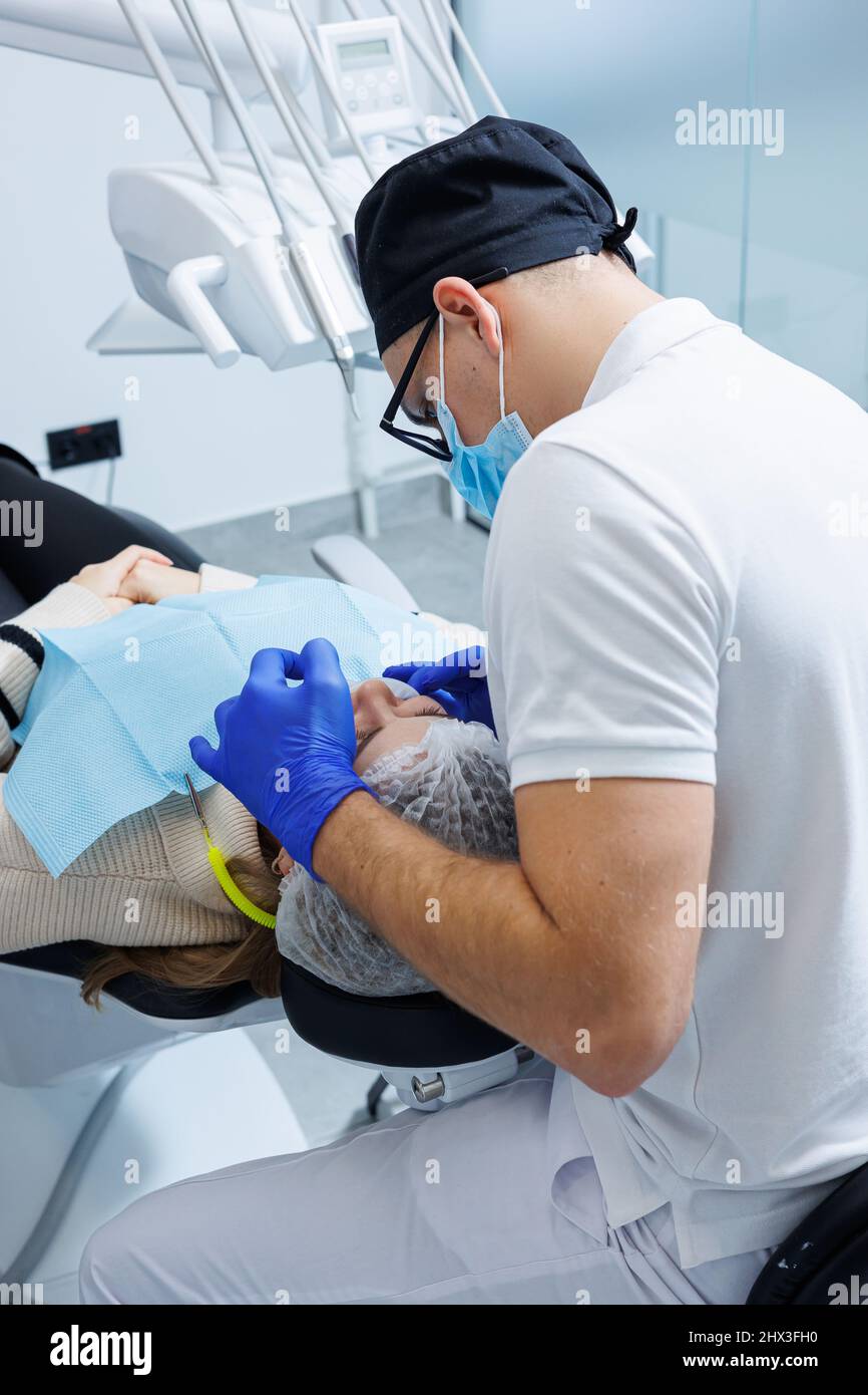 A professional dentist examines a patient's teeth with dental equipment ...
