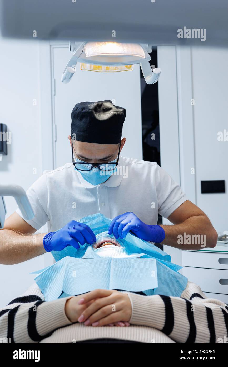 A professional dentist examines a patient's teeth with dental equipment ...