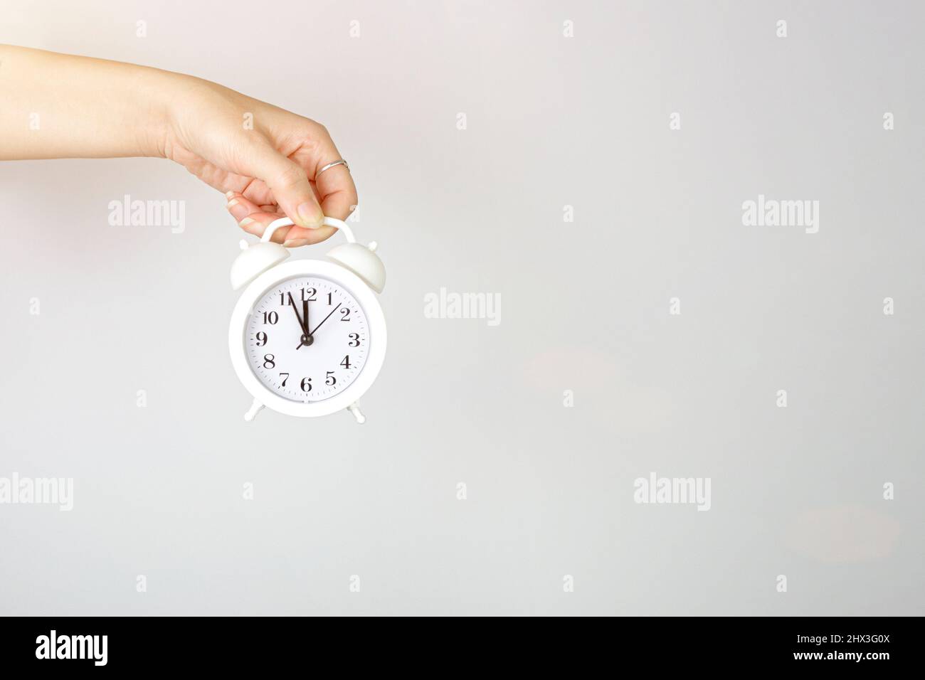 Hand holds little white alarm clock in hand, shows how much time left ...
