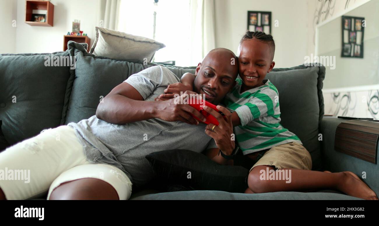 Black father and child together looking at cellphone video. African ...