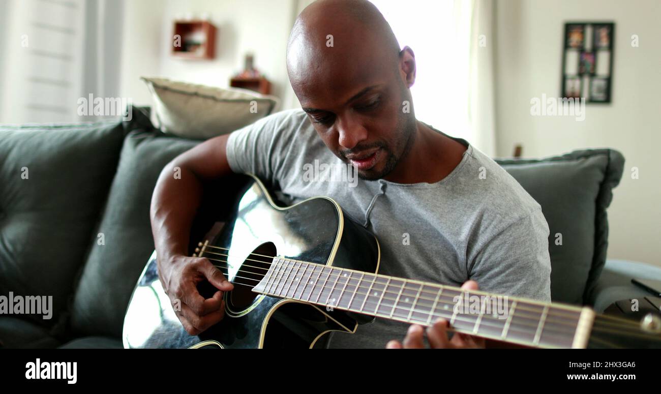 Black man practicing guitar at home. African mixed race learning to ...