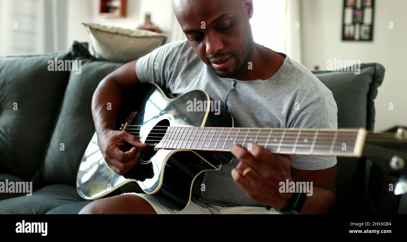 Black man practicing guitar at home. African mixed race learning to ...
