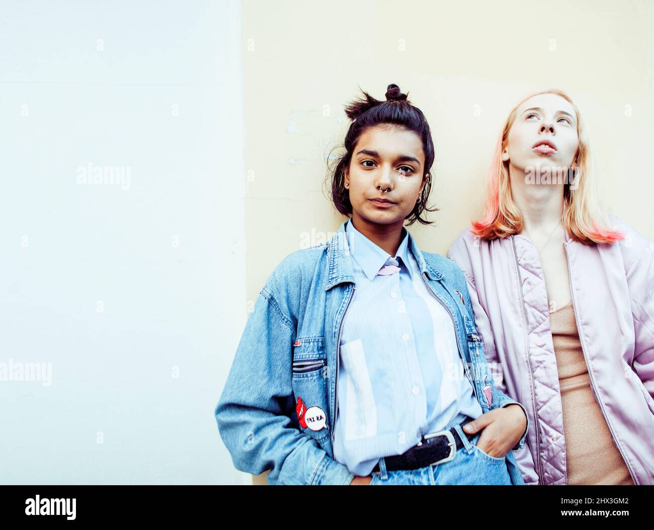 Two teenage girls infront of university building smiling, having fun ...