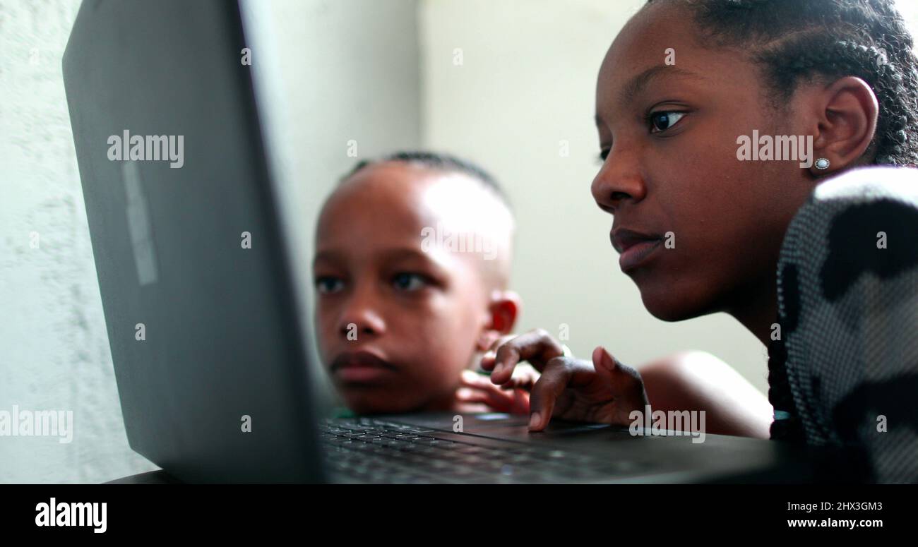 Black teen girl staring at computer screen, little brother watching ...