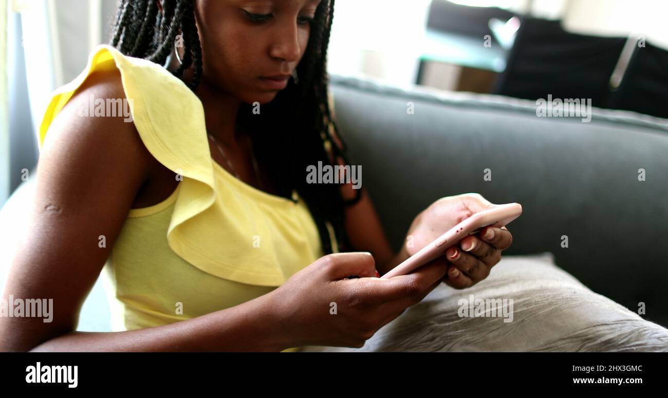 Black teenager girl using cellphone at home couch. African teen girl on ...