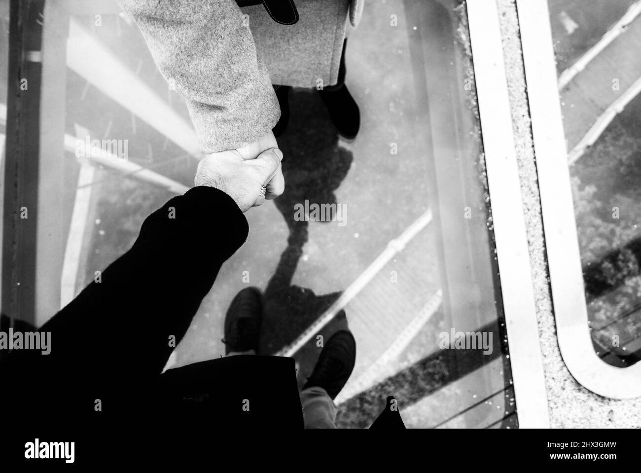 Couple holding hands standing on a glass bridge Stock Photo - Alamy