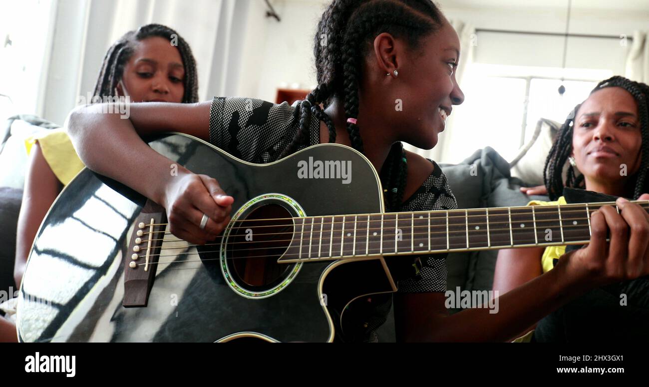 Casual black African family bonding thogether through music guitar ...