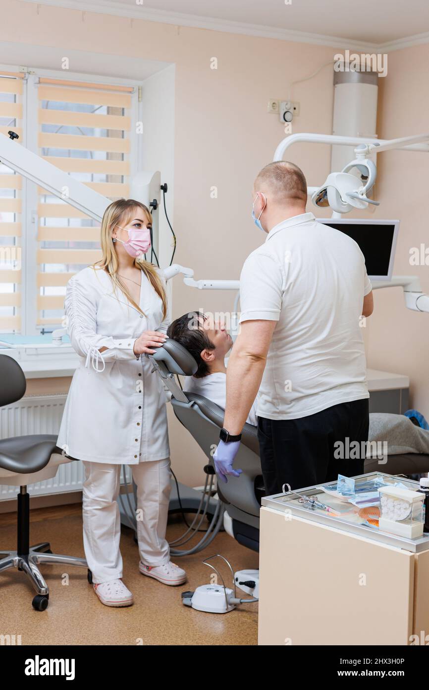 The dentist doctor looks at the patient's teeth and holds dental ...