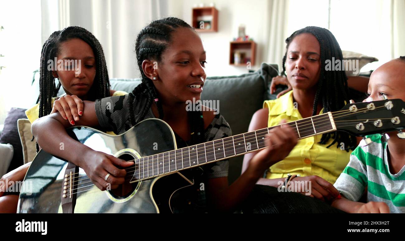 Casual black African family bonding thogether through music guitar ...