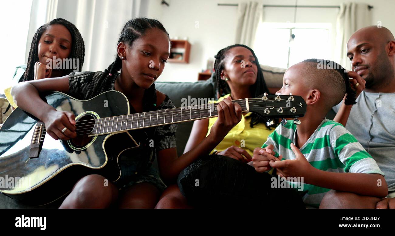 Casual black African family bonding thogether through music guitar ...