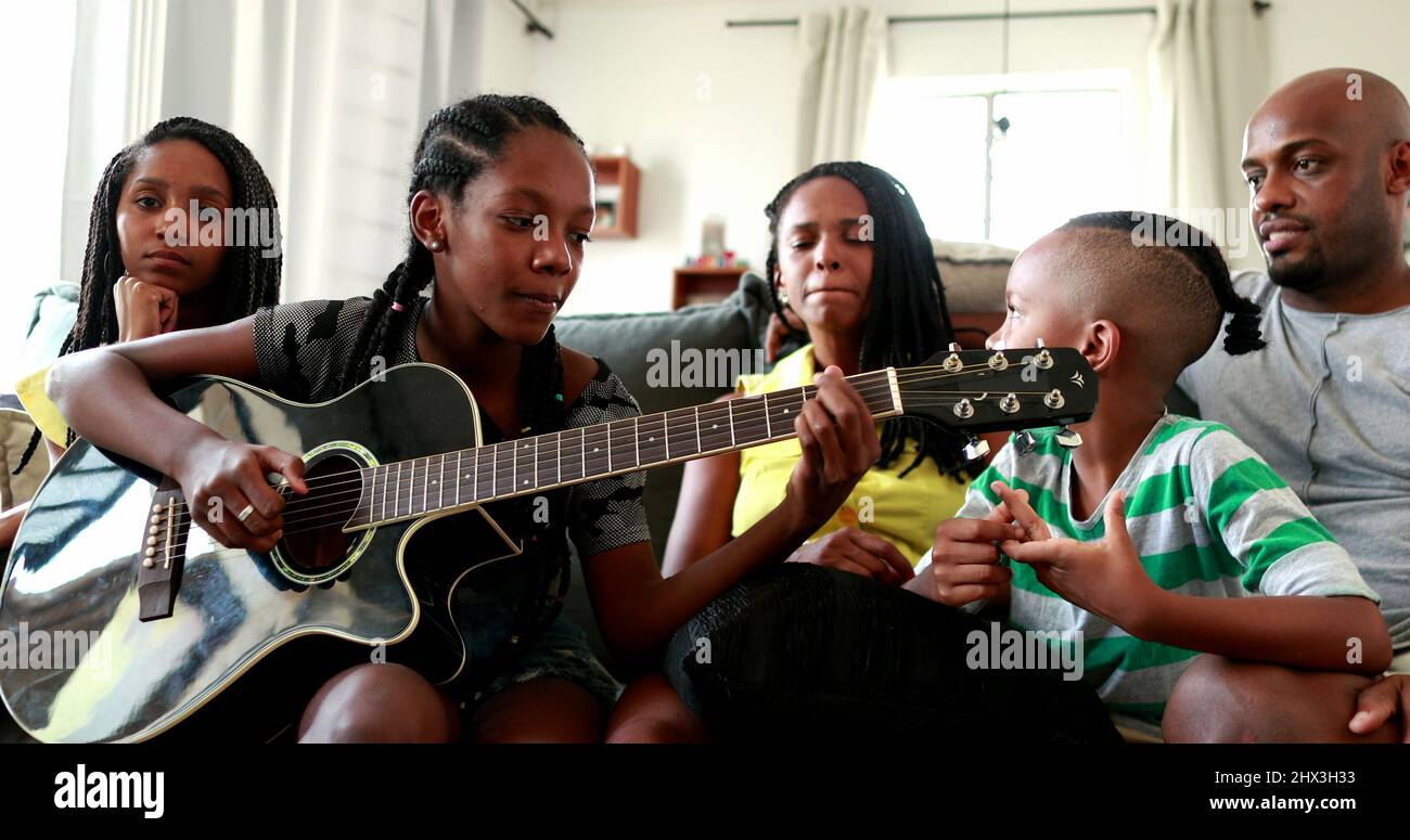 Casual black African family bonding thogether through music guitar ...