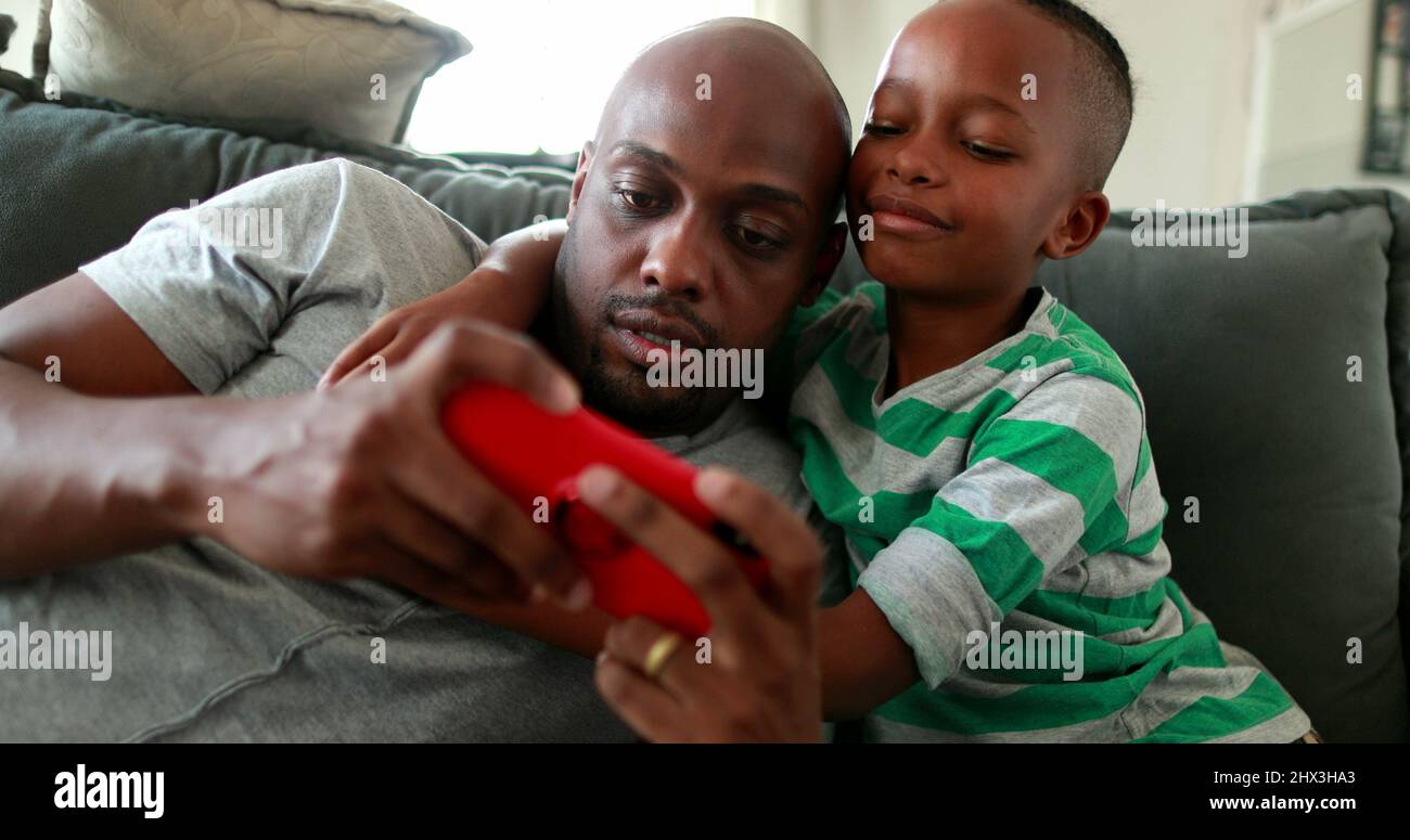 Father and child together watching content on smartphone device ...