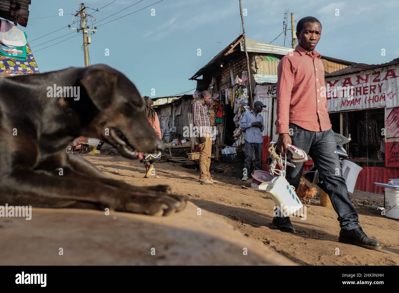 An electronics vendor walks past a sleeping stray dog by the streets in ...