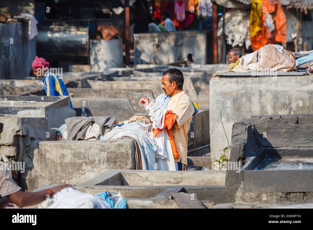 A dhobi wallah (washerman) works gathering up clothes in a typical ...