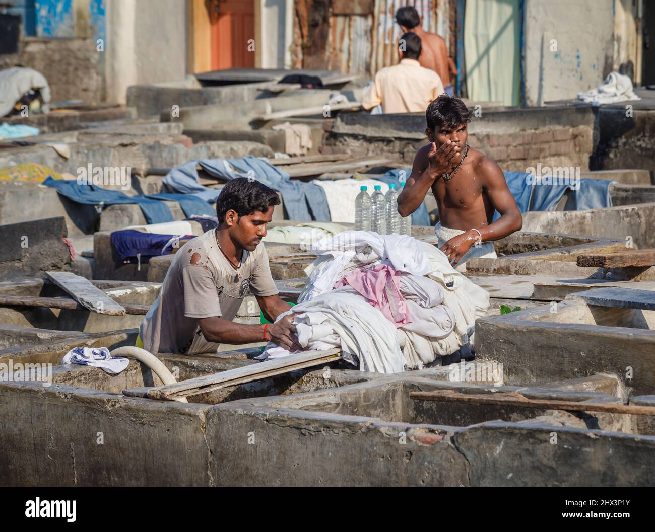 A dhobi wallah (washerman) works washing clothes in a typical concrete ...