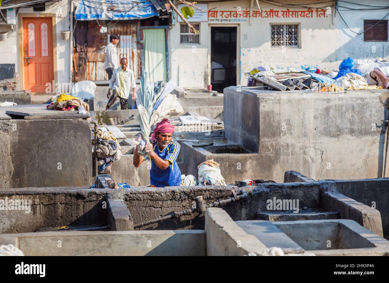 A dhobi wallah (washerman) works washing materials in a typical ...