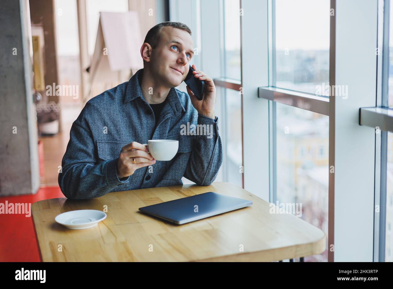 Cheerful IT professional with laptop talking on smartphone to discuss ...