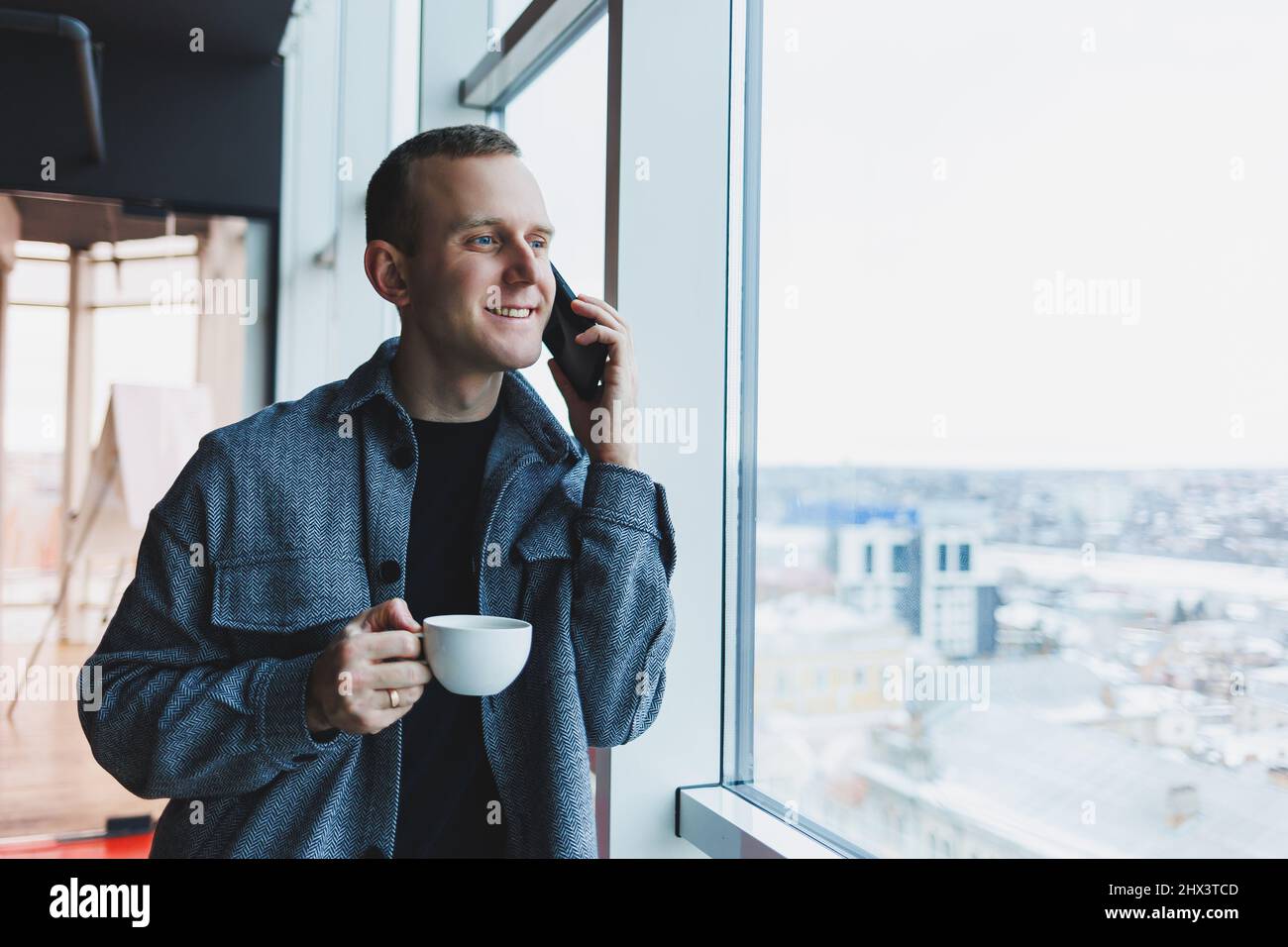 A handsome man of European appearance in a casual suit drinks coffee ...