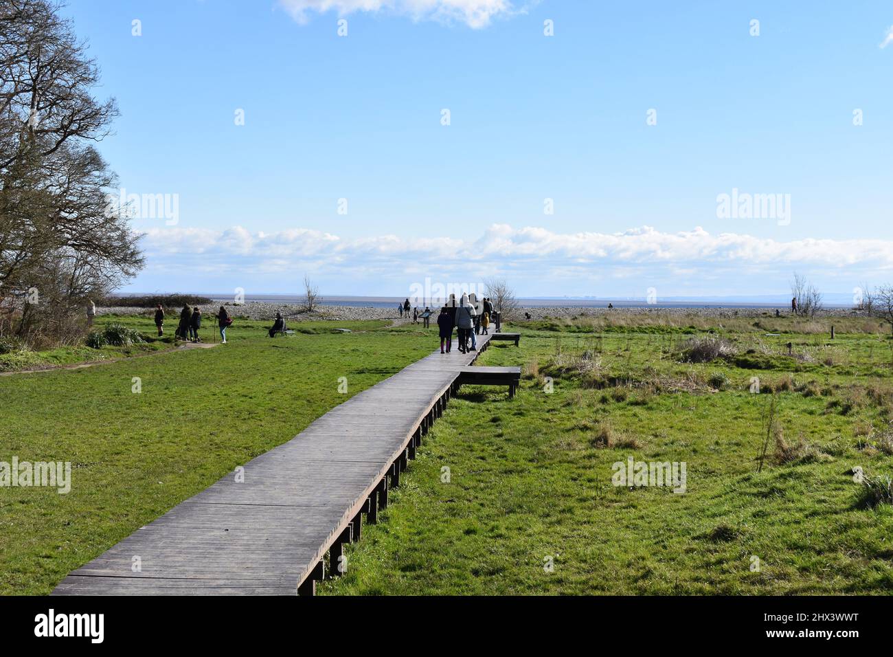 People walking along the wooden boardwalk towards the beach in ...