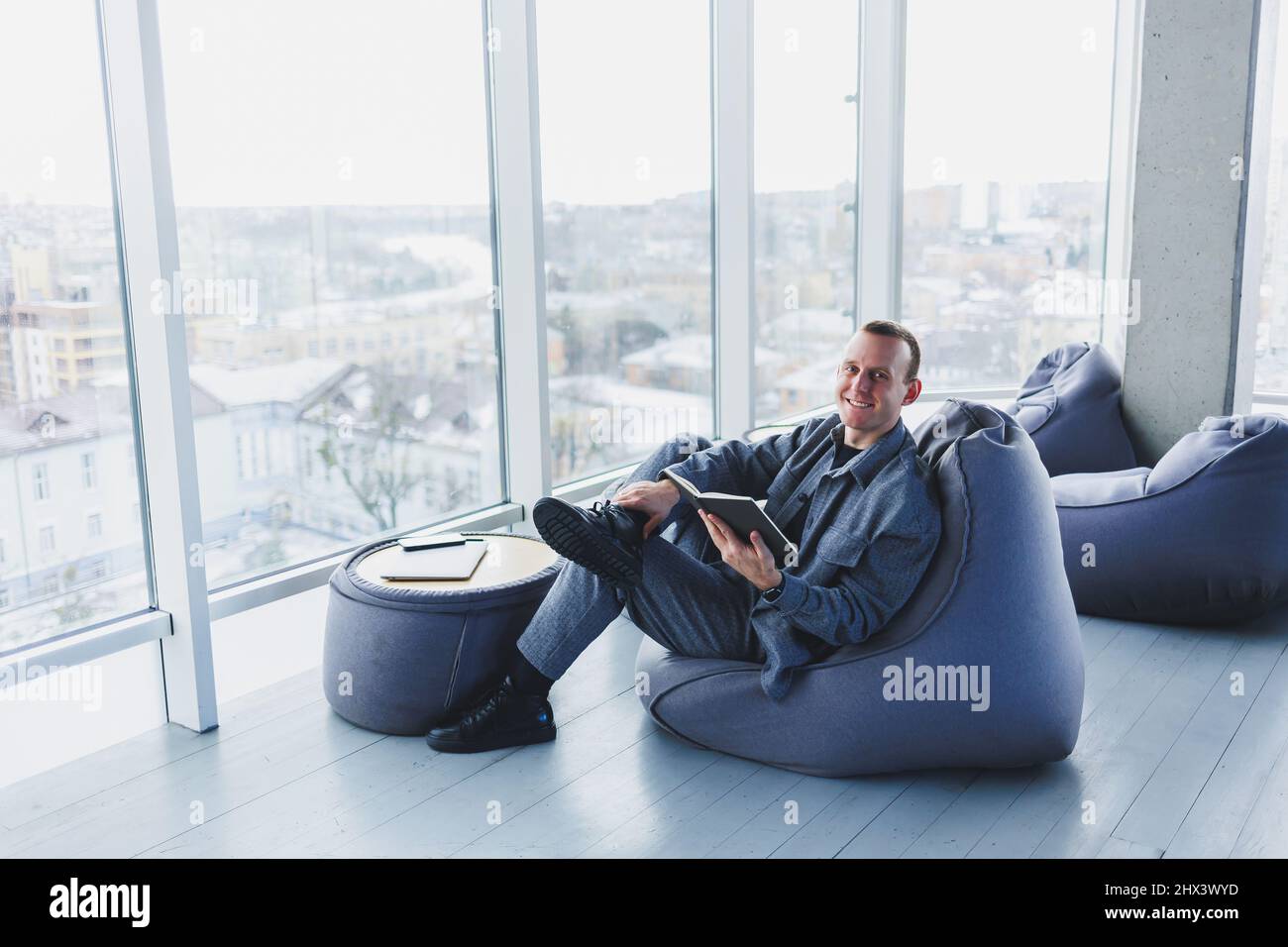 A male businessman in a casual suit resting in a comfortable pouf while ...