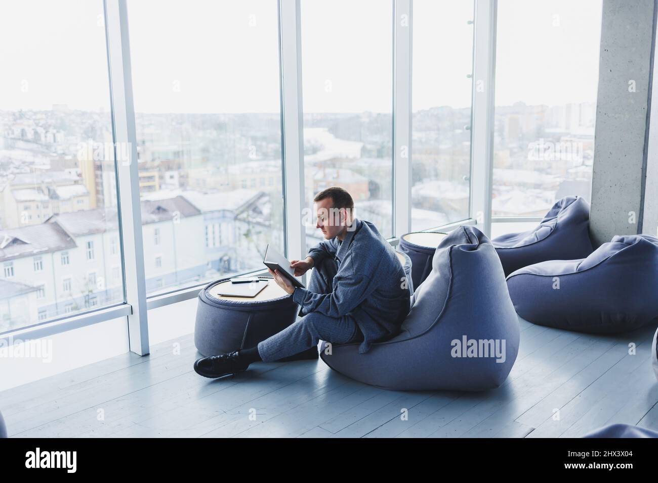 A male businessman in a casual suit resting in a comfortable pouf while ...