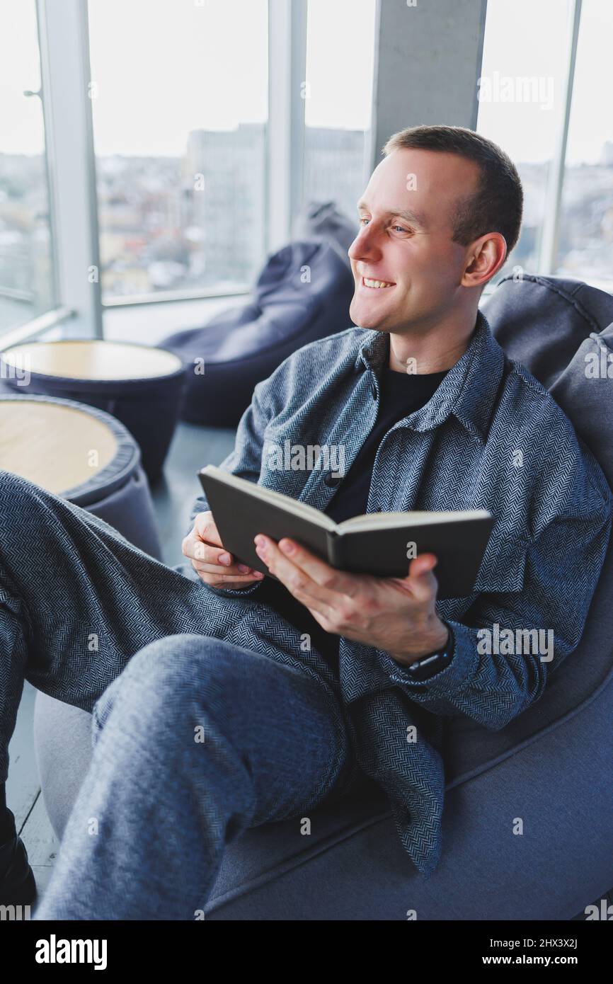 A male businessman in a casual suit resting in a comfortable pouf while ...